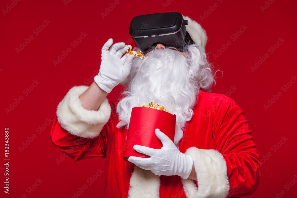 Santa Claus wearing virtual reality goggles and a red bucket with ...