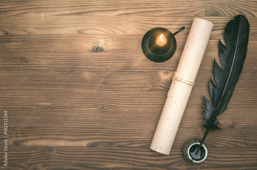 Scroll of paper page, black feather pen and inkwell on table background ...