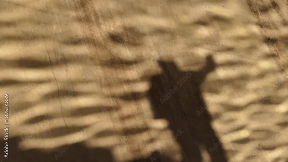 Shadow of man waving a hand goodbye on slow wave reflection pattern ...