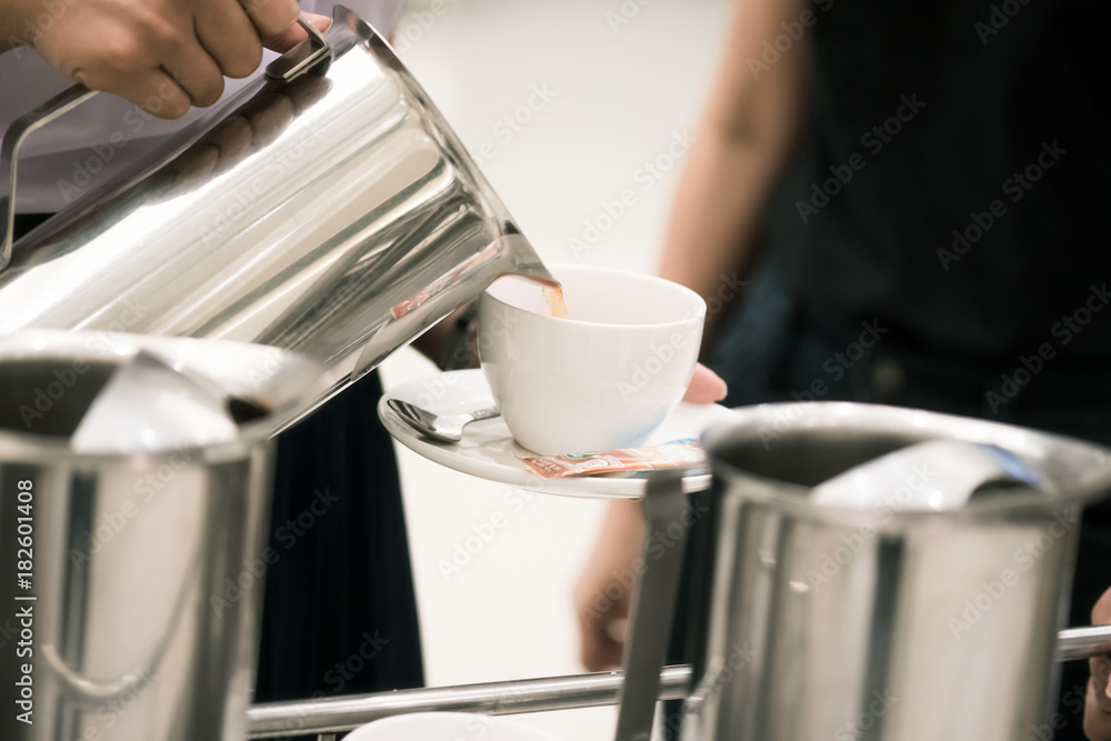 woman staff is pouring coffee in pot to serve guests attending seminar ...