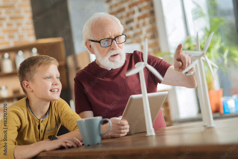 Sharing knowledge. Nice wise elderly man pointing at the windmill model ...