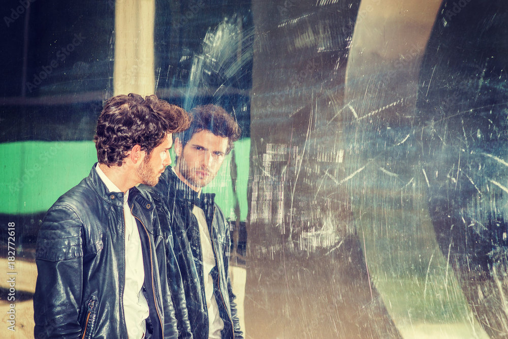 Man looking at mirror. A young handsome guy with beard, walking by ...