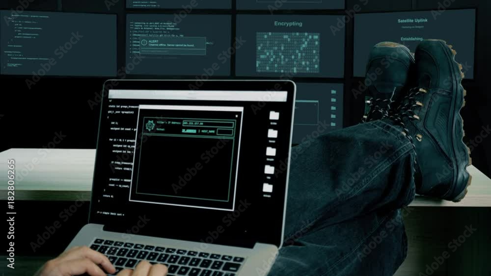 Hacker feet up to table. Hacker with laptop coding exploit to crack code. Man in military shoes ...