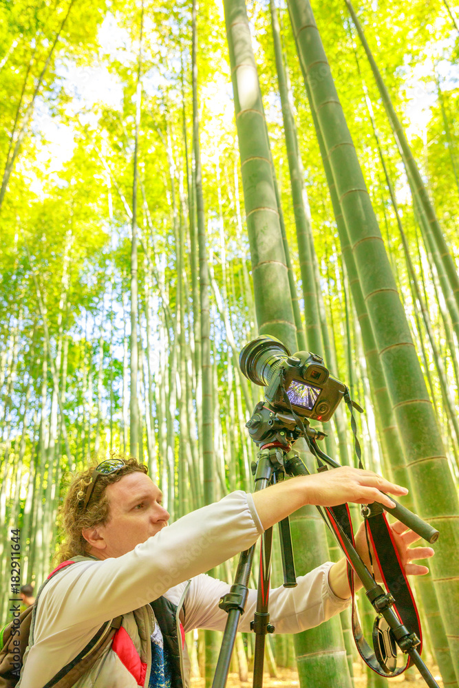 Vertical shot of man photographer with professional camera on tripod in ...