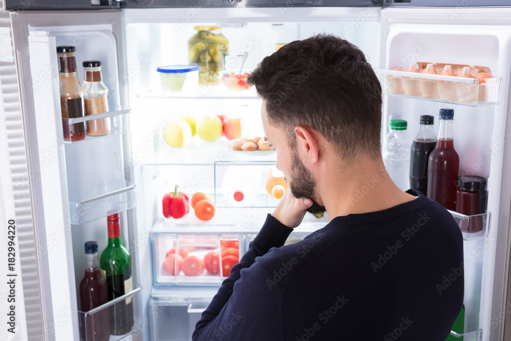 Confused Man Looking At Food In Refrigerator Stock Photo | Adobe Stock