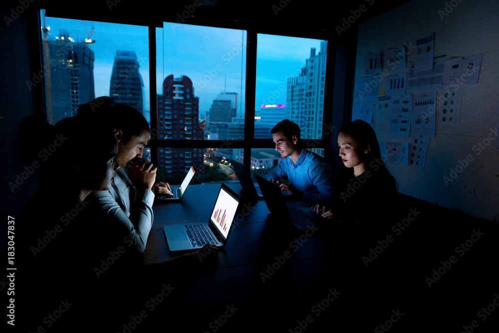 Foto de Working overtime concept. Group of young business team working ... Foto de Working overtime concept. Group of young business team working ...