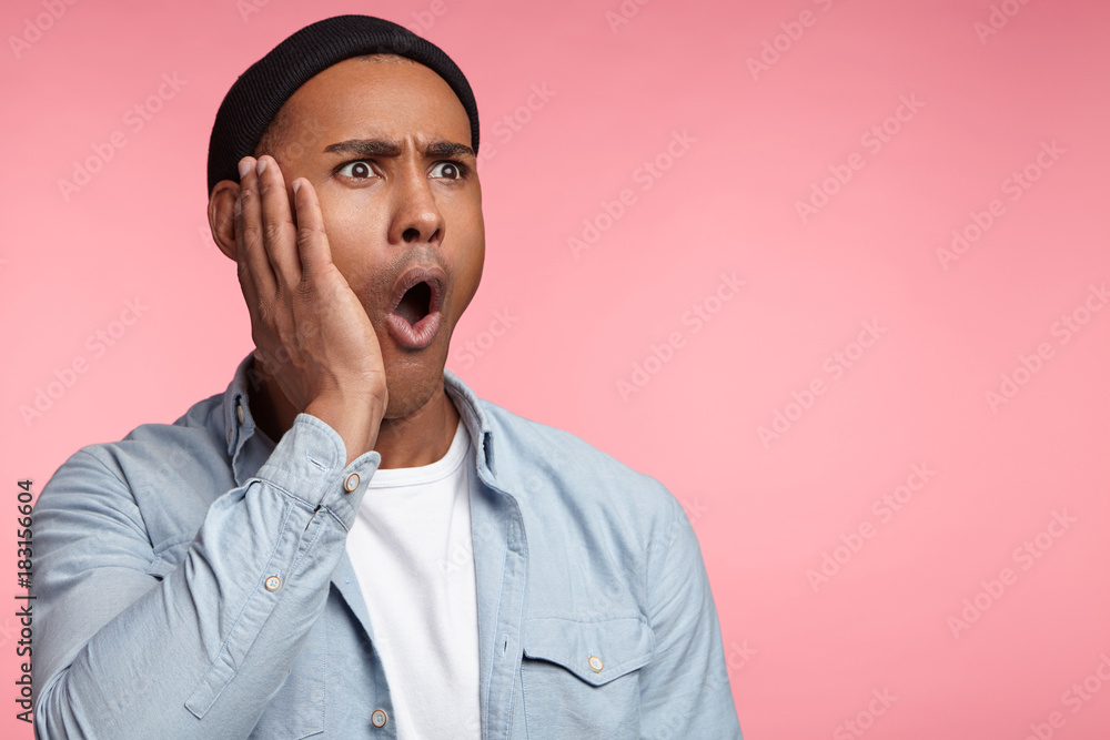 Hipster stylish guy has tanned skin looks with terrible expression ...