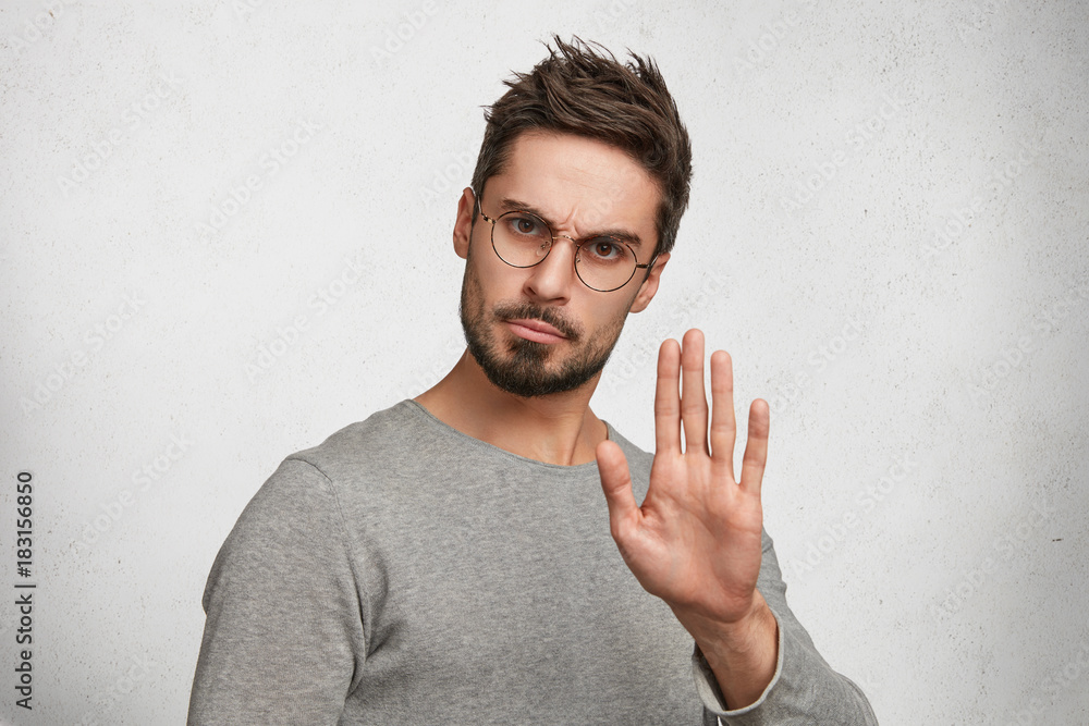 Angry male model gestures indoor, shows stop sign with palm, denies to ...