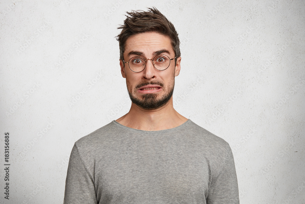 Worried indignant bearded male can`t understand something, has puzzled ...