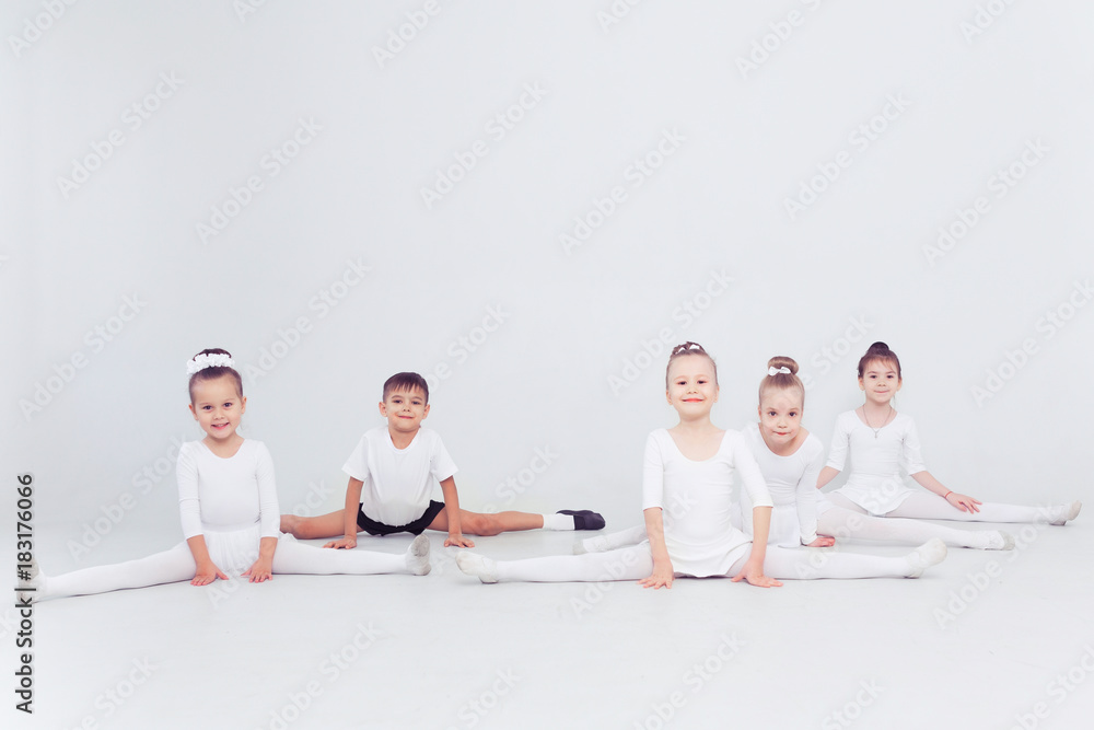 Little ballerinas girls and boy doing splits on white floor, copy space ...