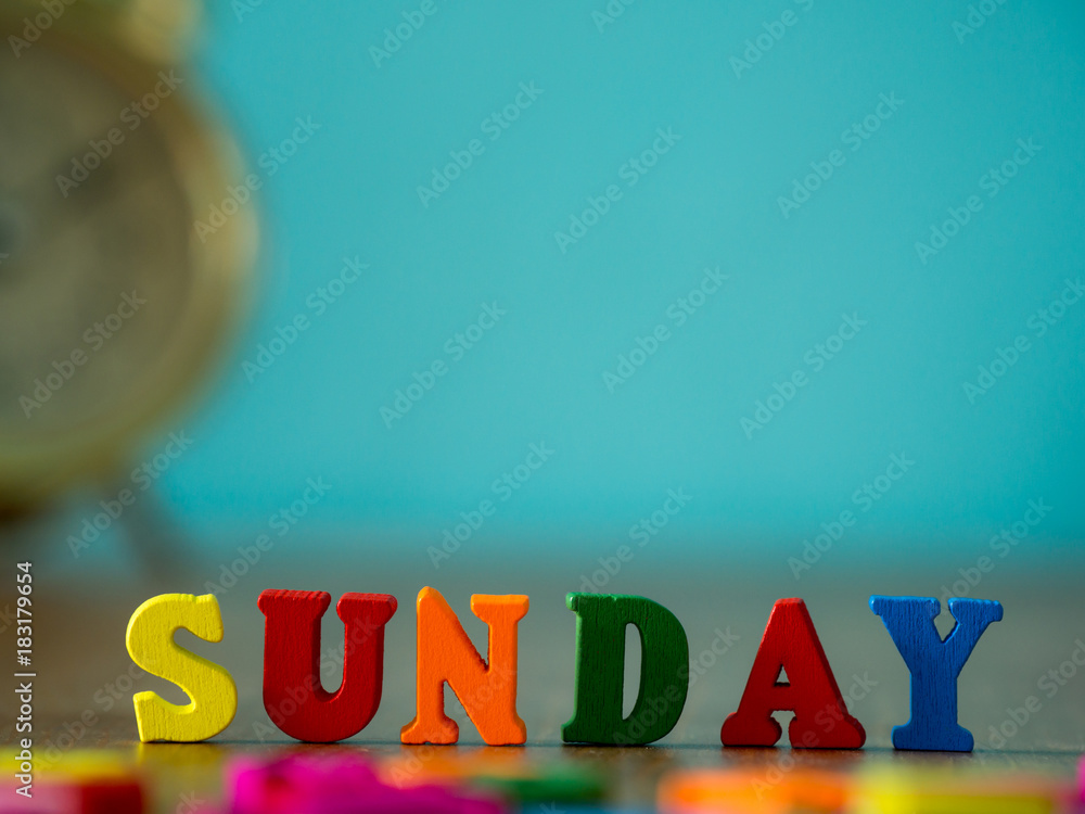 Colorful wooden word SUNDAY on wooden table and vintage alarm clock and ...