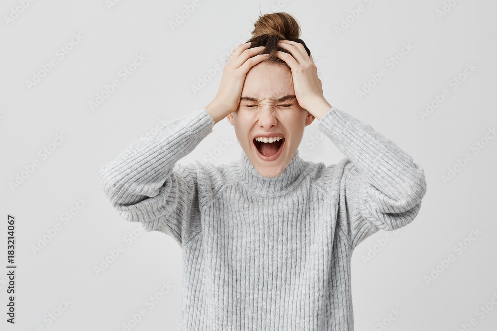 Headshot of frustrated female 30s screaming grabbing her head ...