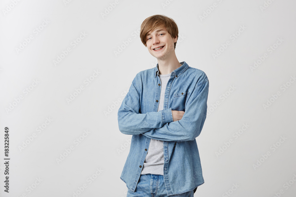Positive young man in denim shirt with fair hair and blue eyes, shy ...