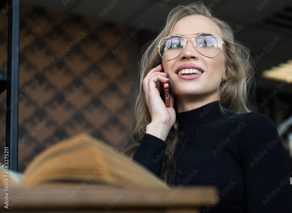 Young charming woman calling with cell telephone while sitting alone in ...