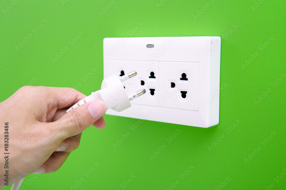 Hand hold electric power plug and inserting into power wall socket ...