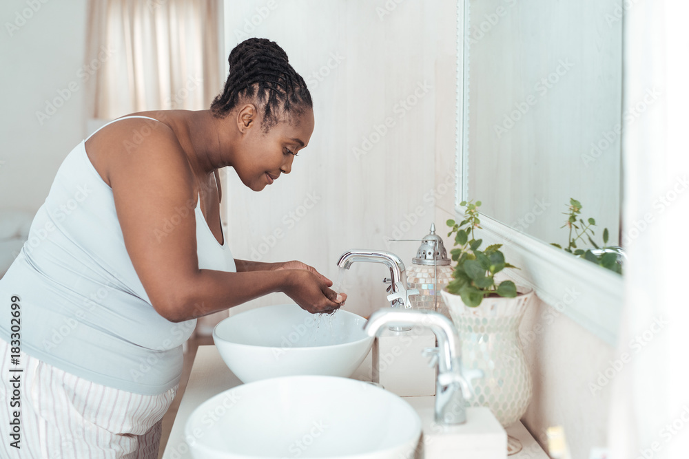 Young African woman washing her face in the morning Stock Photo | Adobe ...