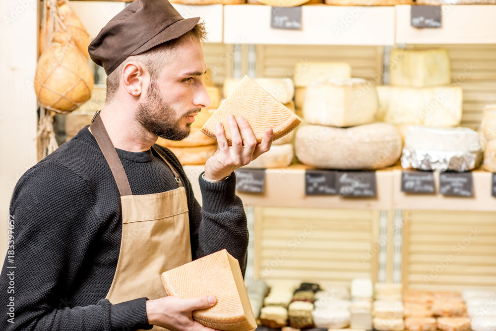 Foto Stock Portrait of a handsome cheese seller in uniform smelling ...
