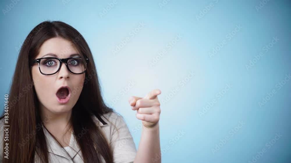 Shocked and surprised young woman pointing with finger at copy space ...