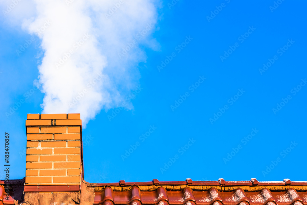 Modern house roof with chimney smoke, air pollution and smog in winter ...