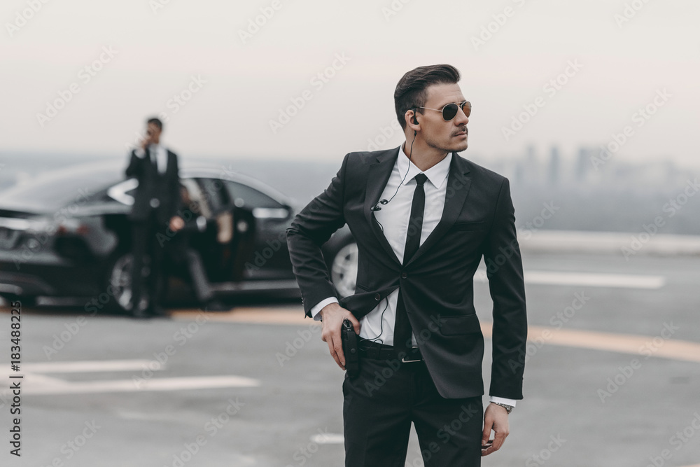 handsome bodyguard with security earpiece putting hand on gun Stock ...