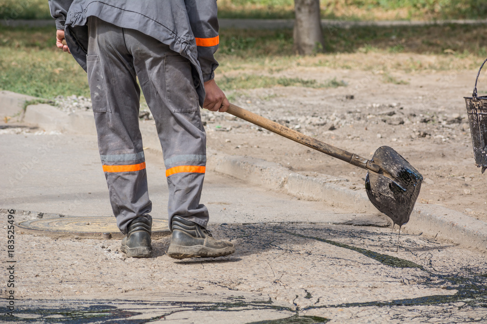 Road repair. Work details, workers pour resin road surface to cover the ...