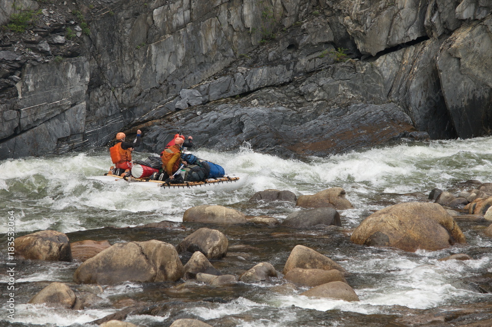 Team of athletes on an inflatable catamaran rafting on river canyon ...