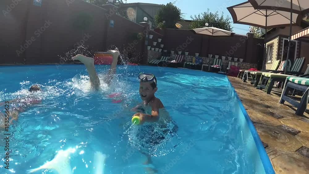 boy shoots from a water pistol in the pool, teenagers have fun in ...