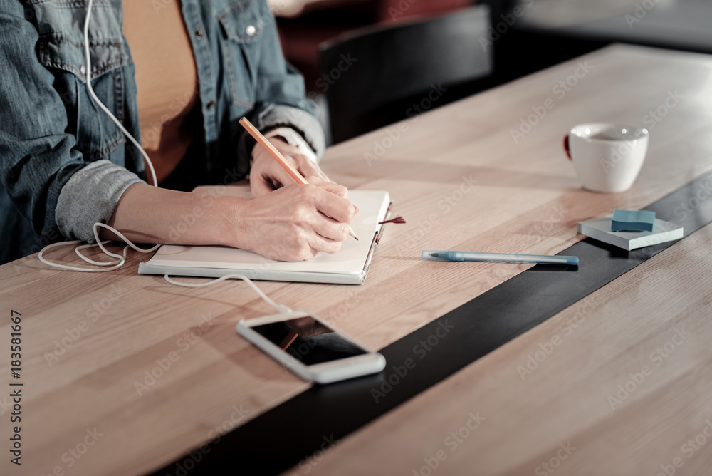 Useful notes. Smart attentive young student sitting and listening to a ...