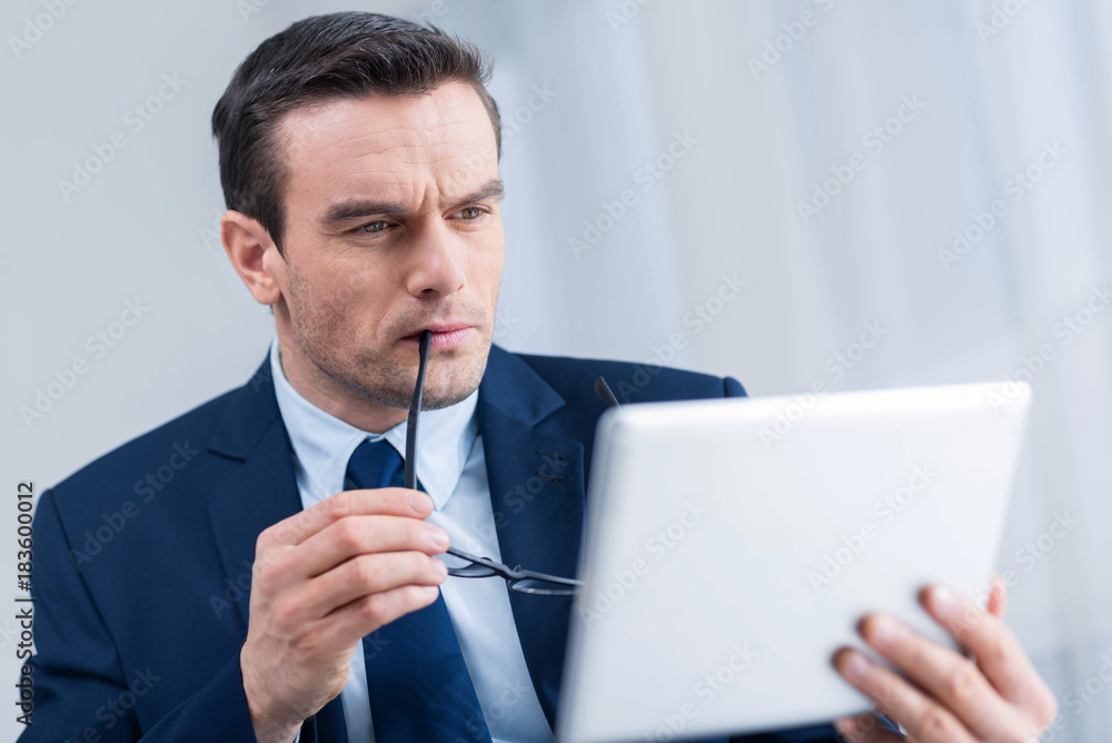 Market situation. Concentrated budding attractive man bitting his ...