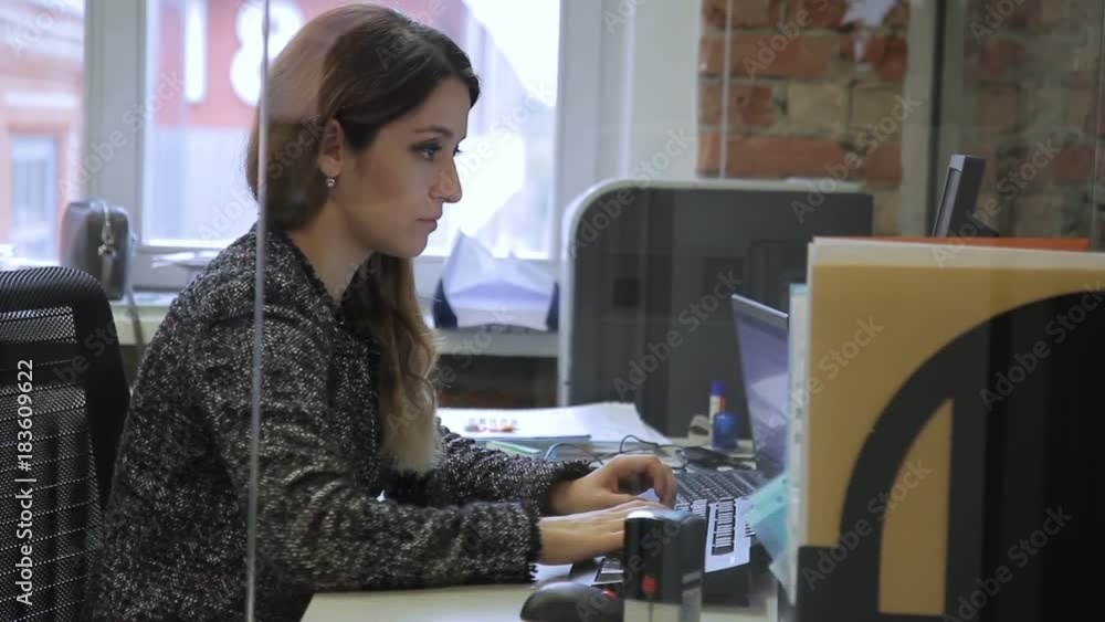 Female employee is working sitting at computer in modern office. Woman ...