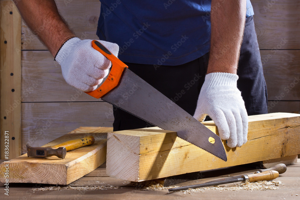 Man hand with saw cutting wooden boards Stock Photo | Adobe Stock