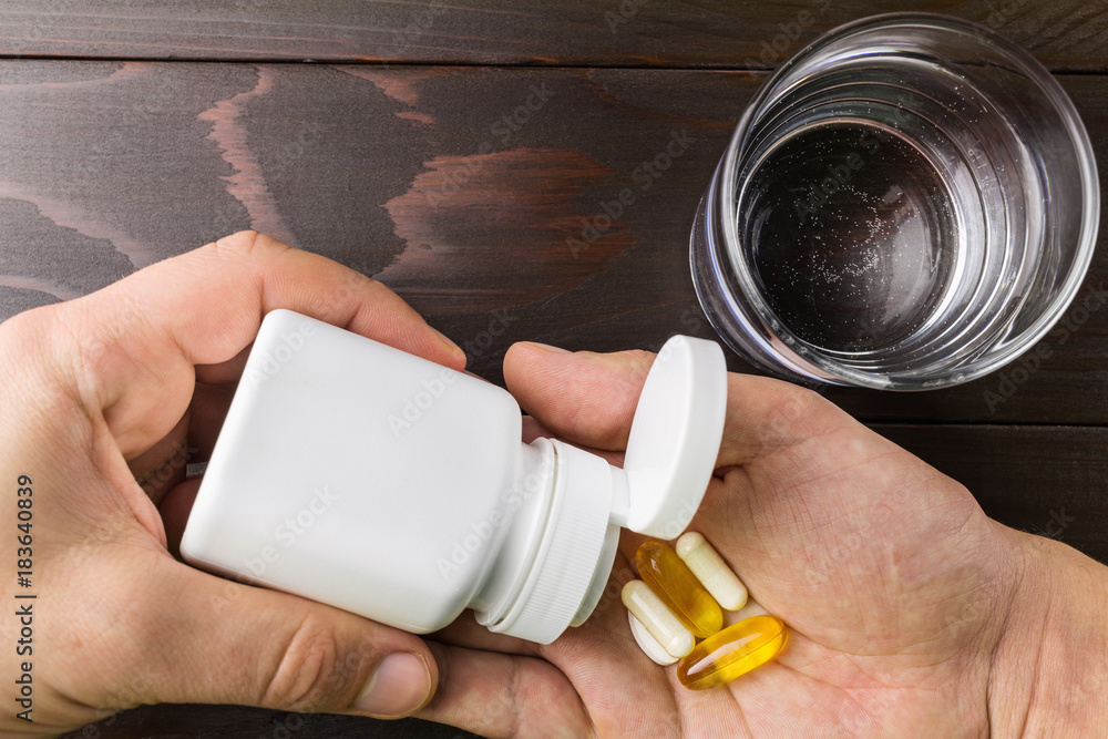 Hands hold vitamin complex and dietary supplement, pours from white ...