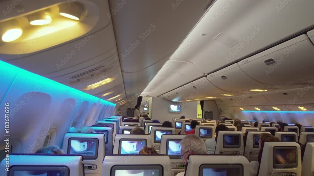 Interior passengers airplane with people on seats. Aircraft cabin with rows of seats. Passengers ...