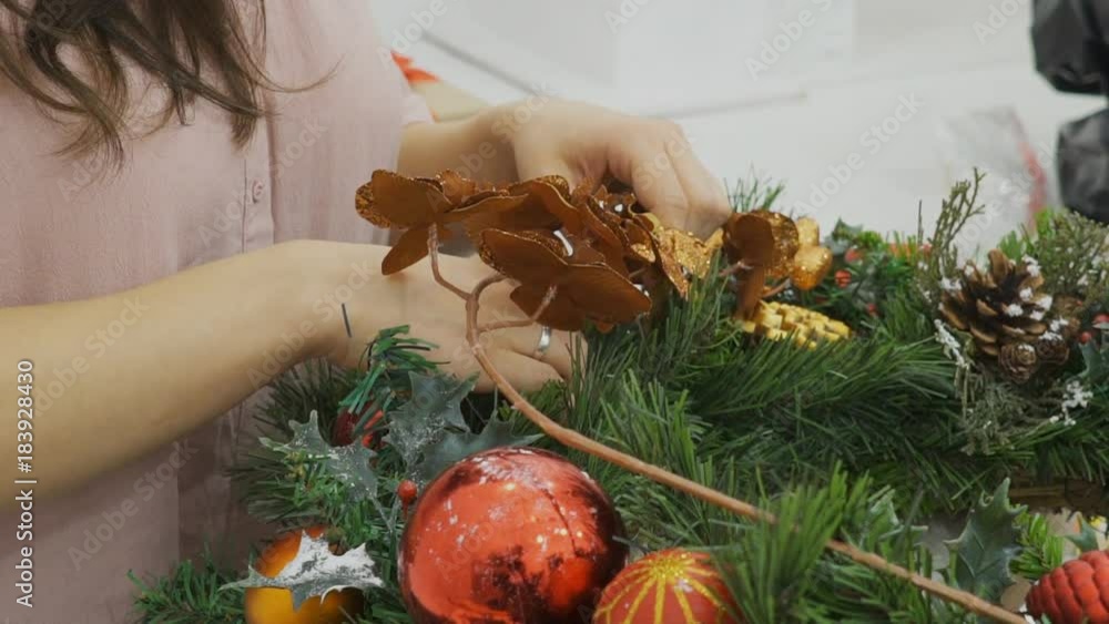 The female designer makes a wreath with imitative fir branches and ...