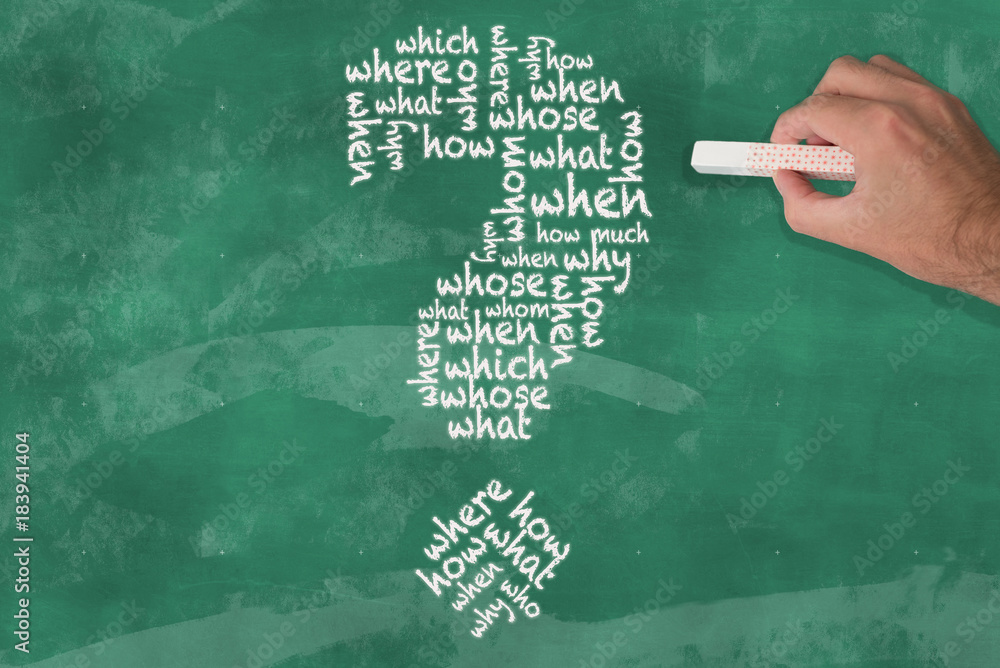 hand holding piece of chalk writing question words in shape of question ...