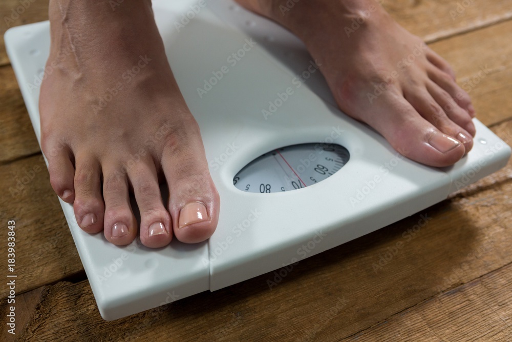 Woman checking her weight on a weighing machine Stock Photo | Adobe Stock