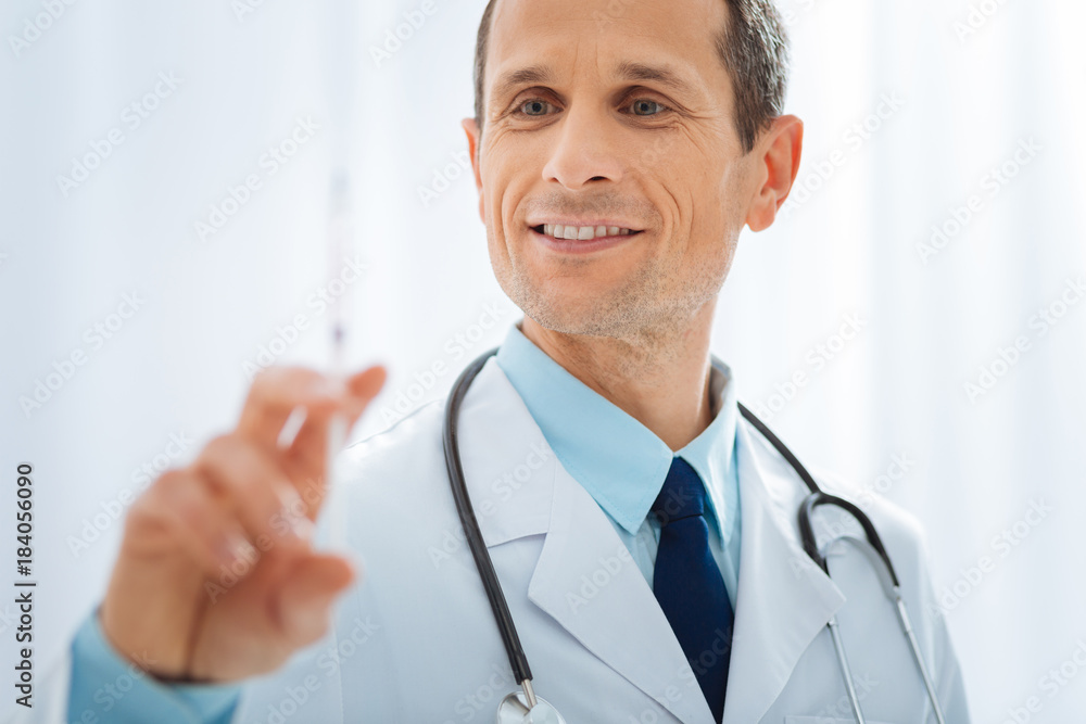 Wait a second. Positive delighted doctor keeping smile on his face and ...