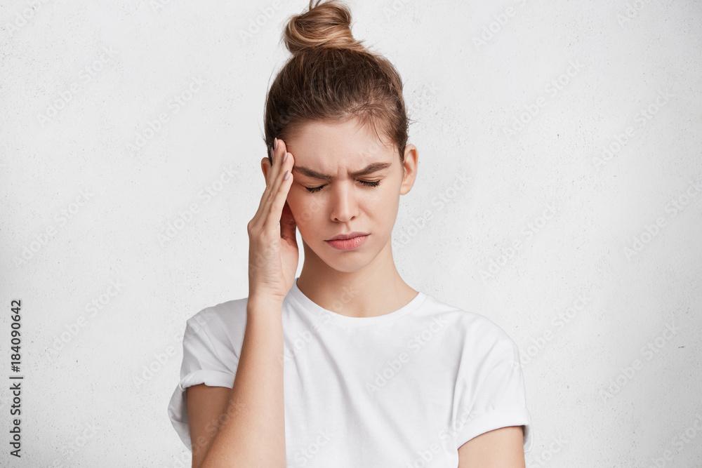 Portrait of tired exhausted young female has terrible headache after ...