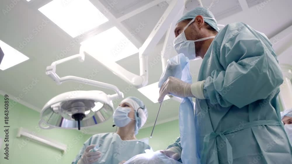two neurosurgeons are in an operating room, carrying out an endoscopic ...