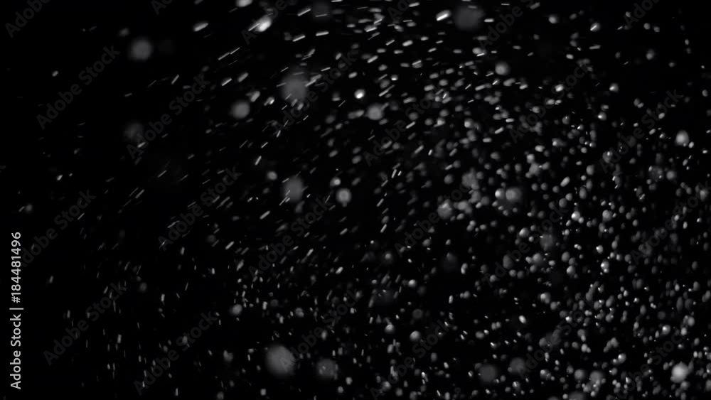 Several snow particles falling down over a black background that you ...