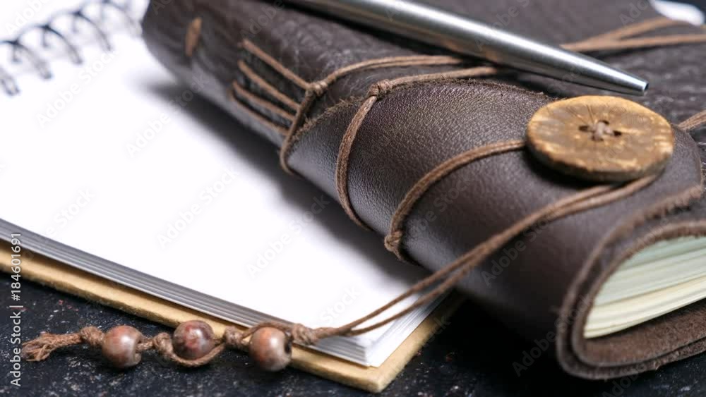 Close up on leather vintage retro notebook on a dark table. Old type ...