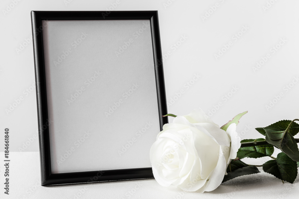 White blank condolence card with black frame and white artificial rose ...