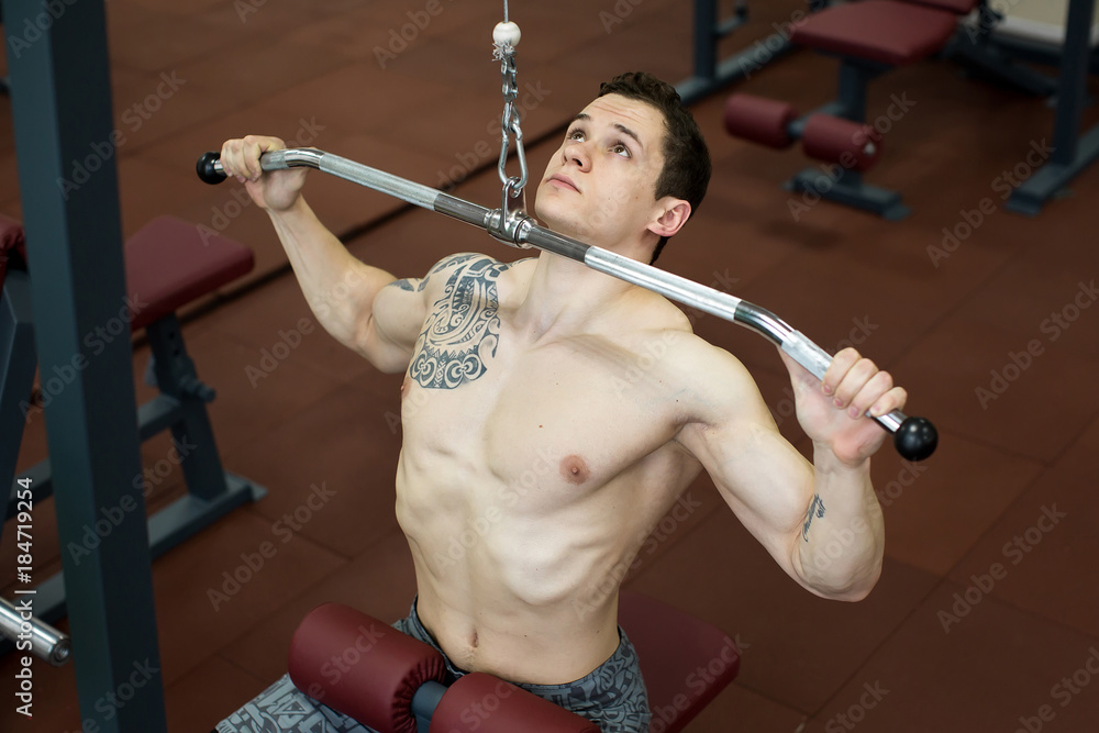.Shoulder pull down machine. Fitness man working out lat pulldown ...