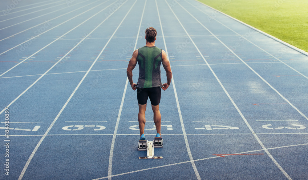 Sprinter standing on starting block on running track Stock-Foto | Adobe ...