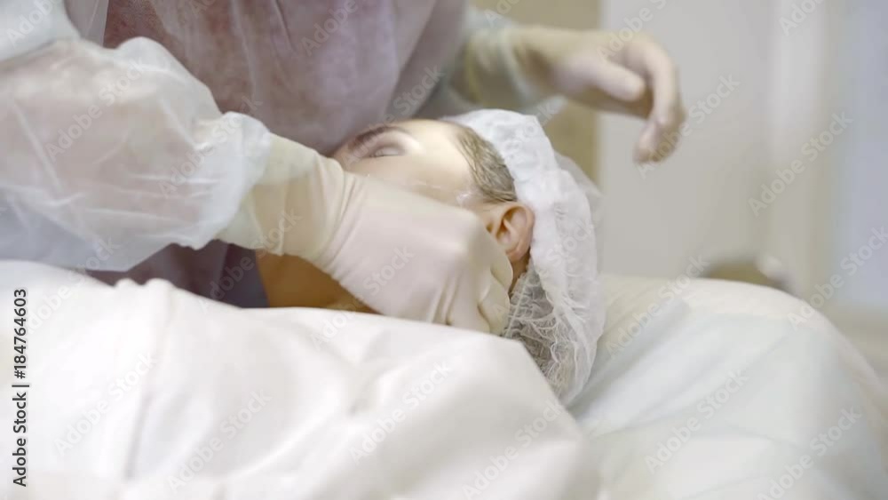 the dermatologist doctor wipes the face of the patient with a ...