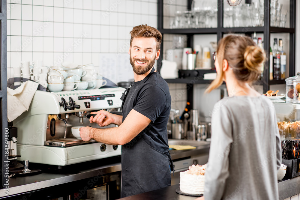 Handsome barista making coffee standing with female client at the bar ...