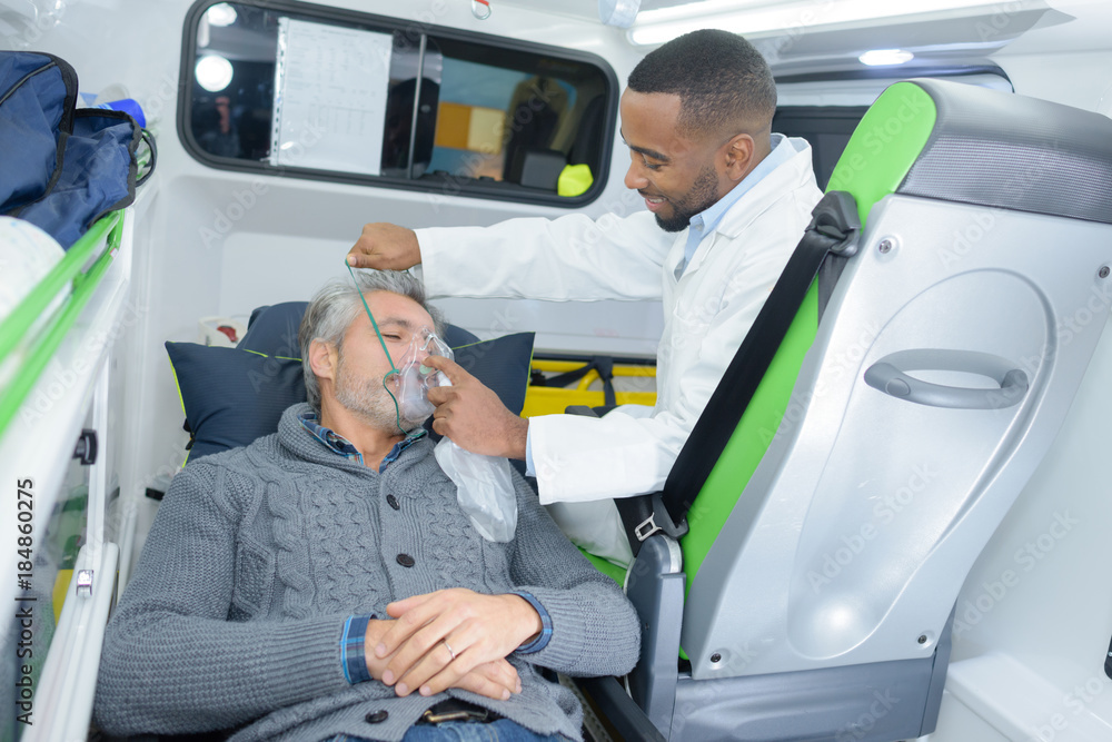paramedic puts oxygen mask on patient in ambulance Stock Photo | Adobe ...