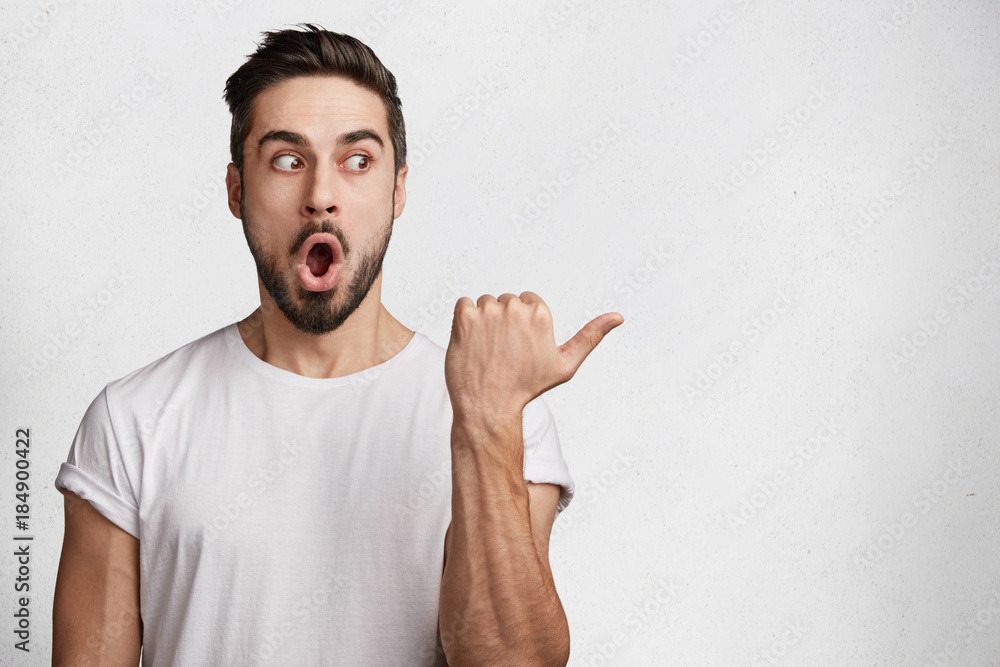 Shocked male model with stubble, keeps mouth widely opened, expresses ...