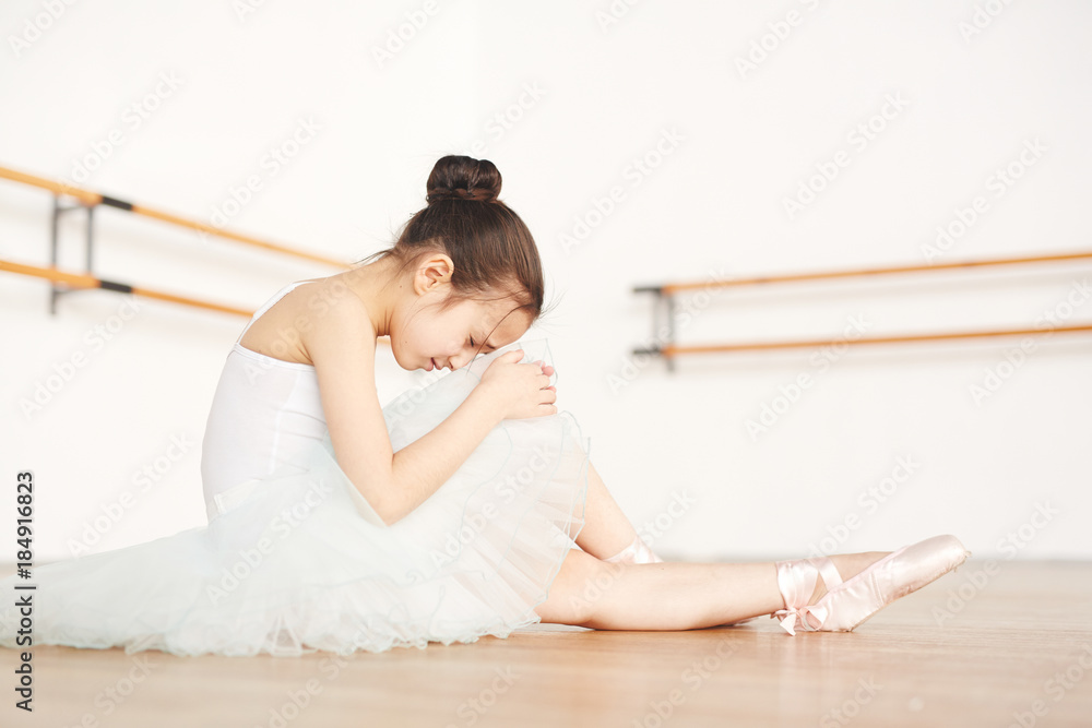 Cute girl in ballerina outfit sitting on the floor of classroom and ...
