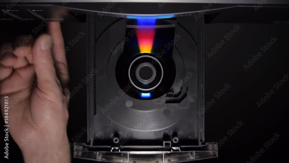 The hand puts the compact disk in the DVD player and after play get it ...